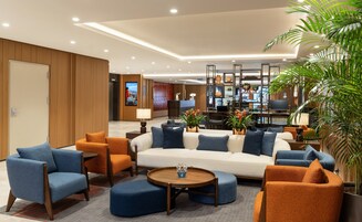 Um hall moderno com balcão de atendimento, área de estar e uma grande planta.