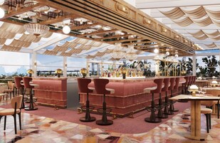 Uma área de bar com teto alto, vários candelabros e balcão com banquetas.