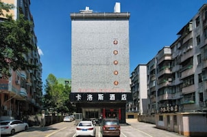 Hotel com uma placa vertical chamativa, vários andares e estacionamento à frente.