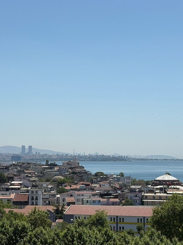 Paisagem costeira urbana com edifícios residenciais densos, uma estrutura em cúpula imponente e horizonte urbano ao longe.