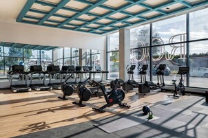 Uma academia com esteiras, bicicletas ergométricas e aparelhos de musculação.