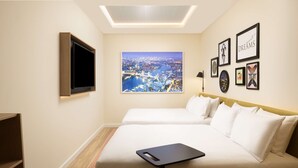 Quarto de hotel com uma cama, uma escrivaninha e um grande quadro com vista urbana na parede.