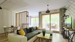 Uma sala de estar moderna com um sofá em forma de L, uma mesa de centro, um espaço de jantar com cadeiras e um aparador com uma planta.