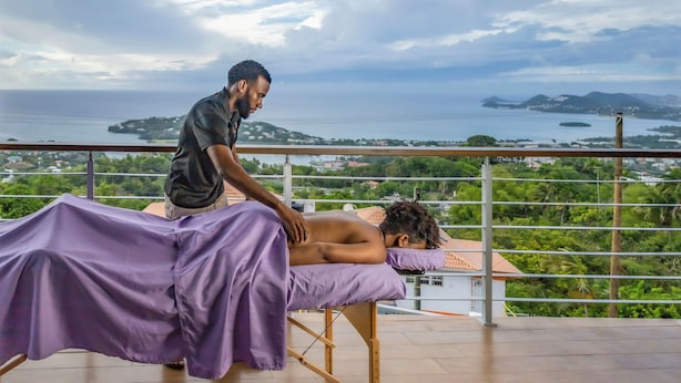Sessão de massagem em varanda com vista panorâmica para o mar e colinas.