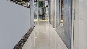 Um corredor limpo e moderno, com piso lustroso, parede de concreto de um lado e uma porta do outro.
