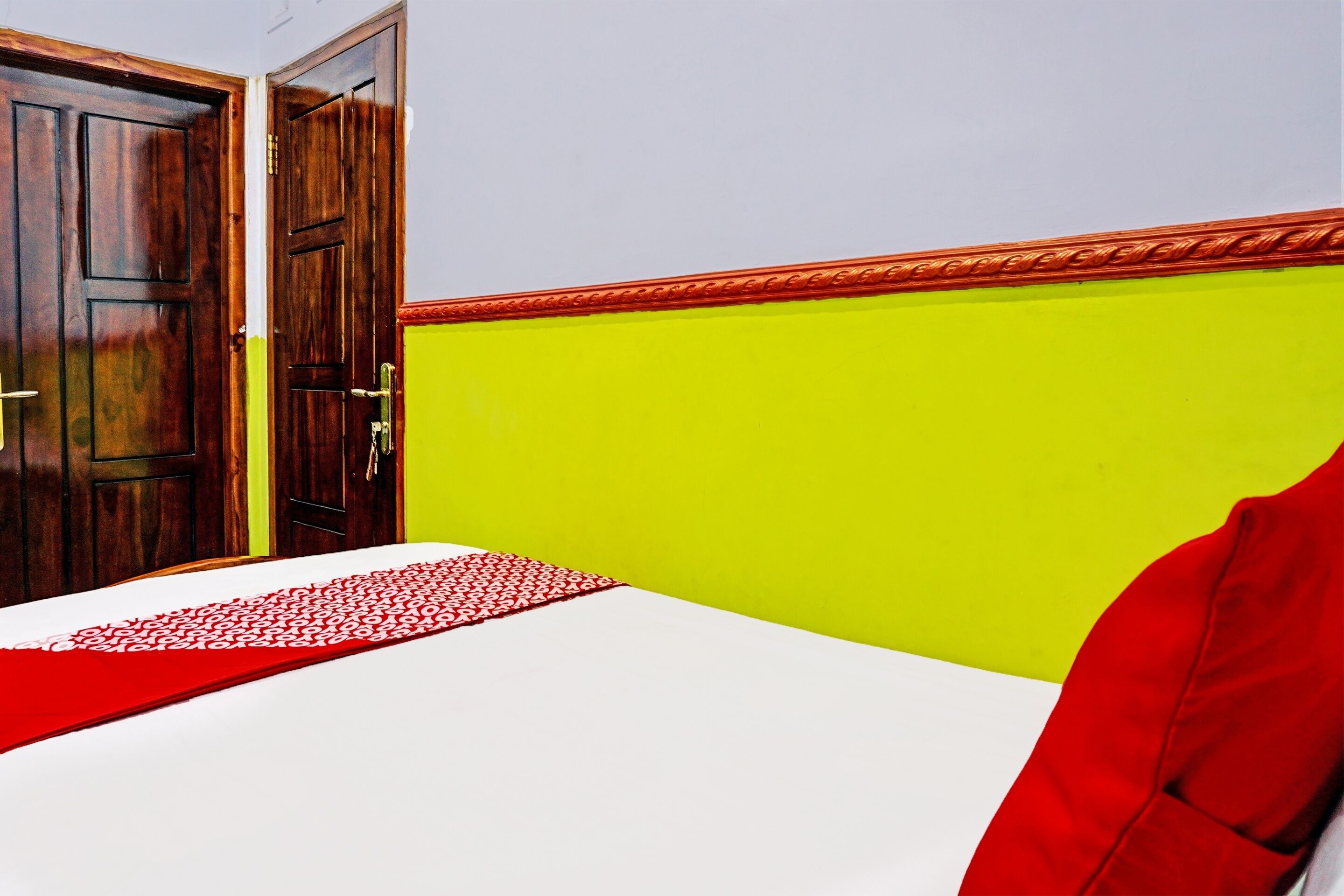 Um quarto com uma cama, uma porta de madeira e uma parede verde vibrante.