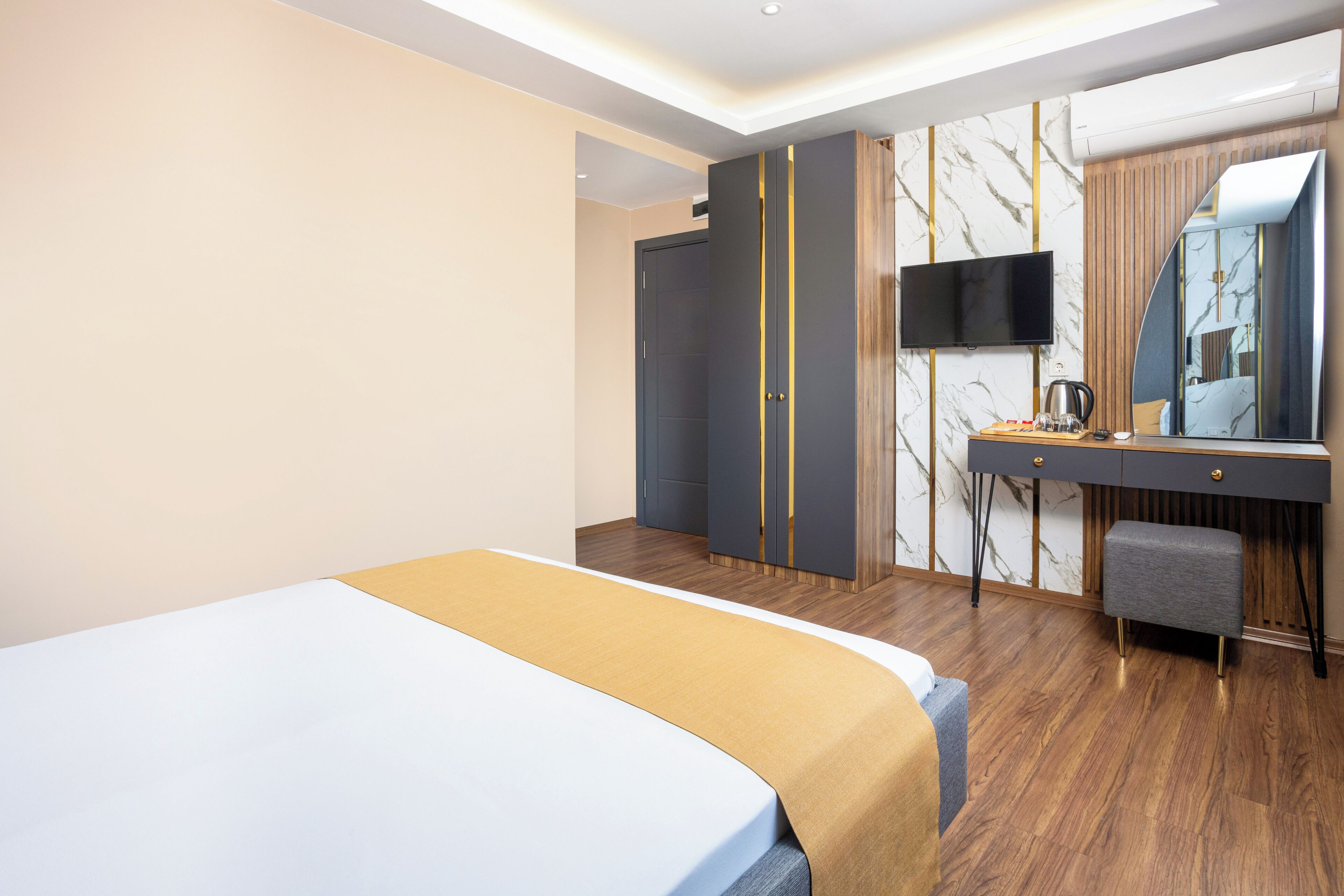 Quarto de hotel moderno com cama, escrivaninha, televisão e guarda-roupa.