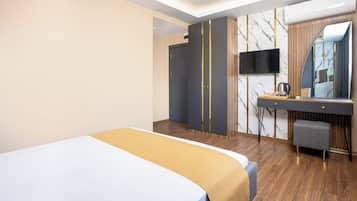 Quarto de hotel moderno com cama, escrivaninha, televisão e guarda-roupa.