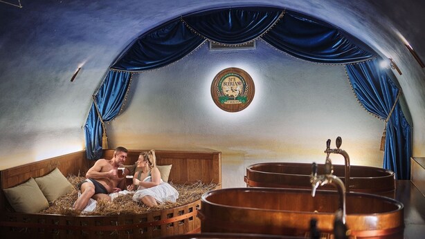 Um quarto acolhedor com uma cama de madeira, uma placa na parede e grandes barris de cobre para cerveja.