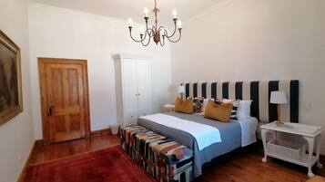 Quarto com cama, lustre, guarda-roupa, mesa de cabeceira e tapete vermelho.