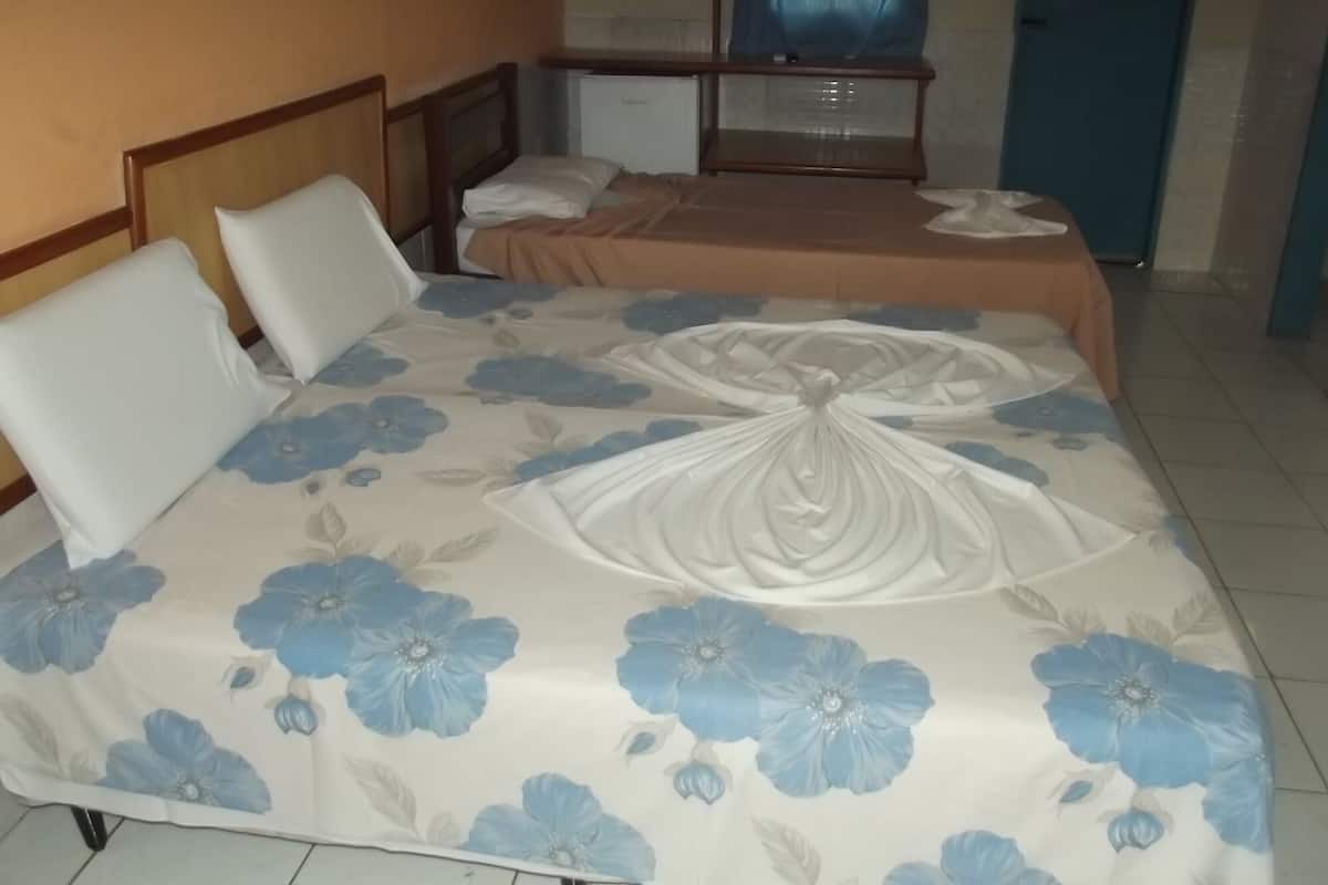 Quarto de hotel com duas camas, cada uma com colcha florida e almofadas brancas.