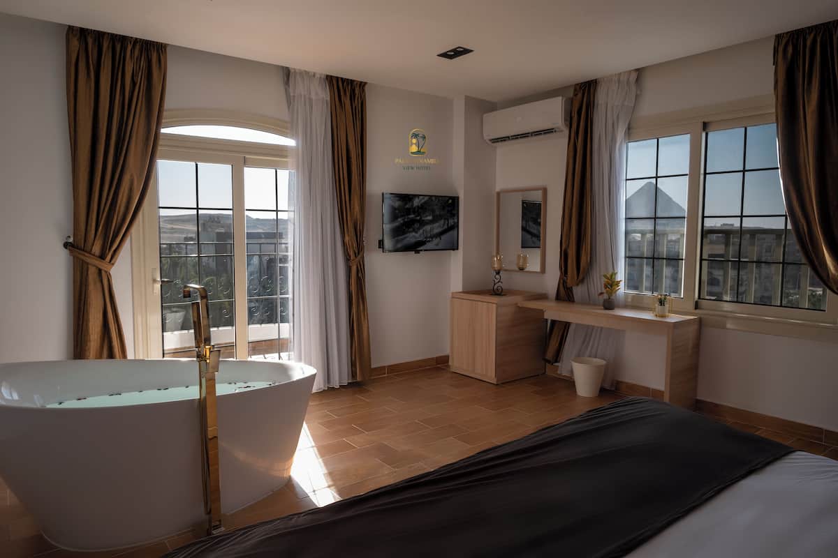 Quarto de hotel moderno com uma banheira grande, toucador com espelho e uma secretária.