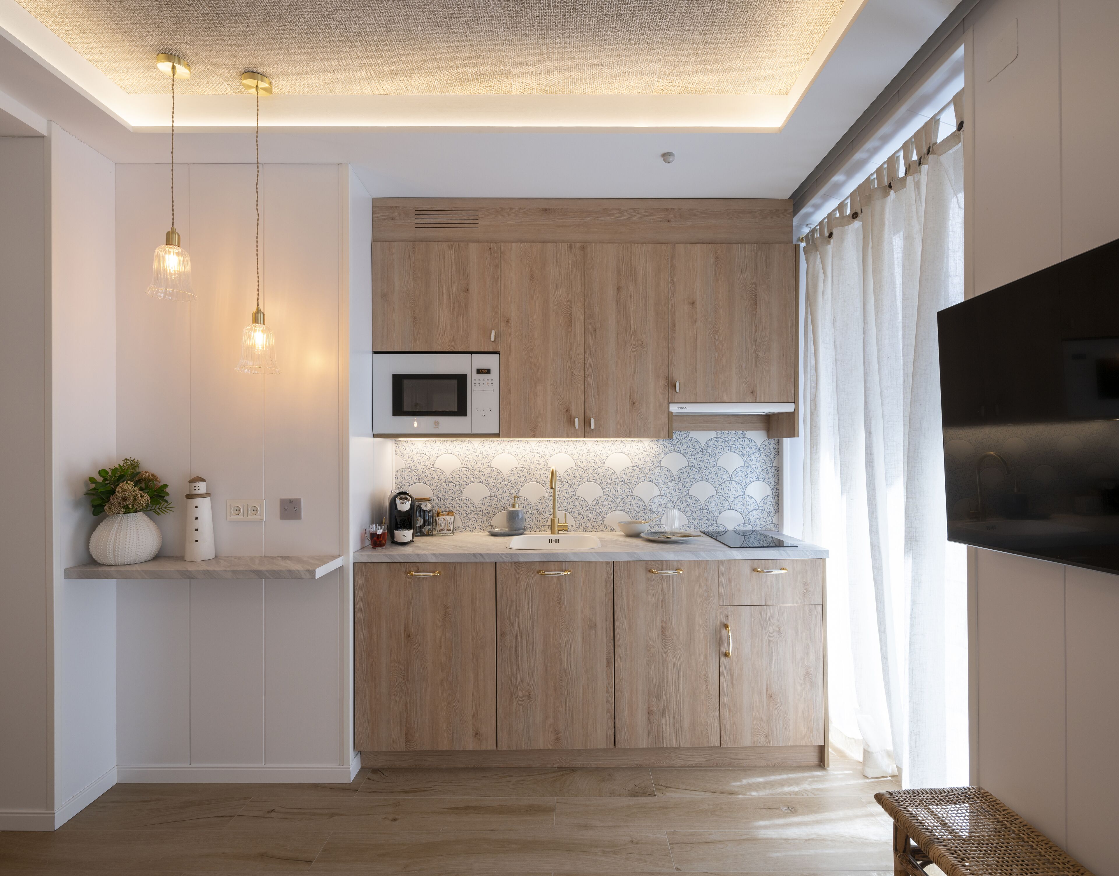 Cozinha moderna com armários de madeira, micro-ondas embutido e iluminação pendente.