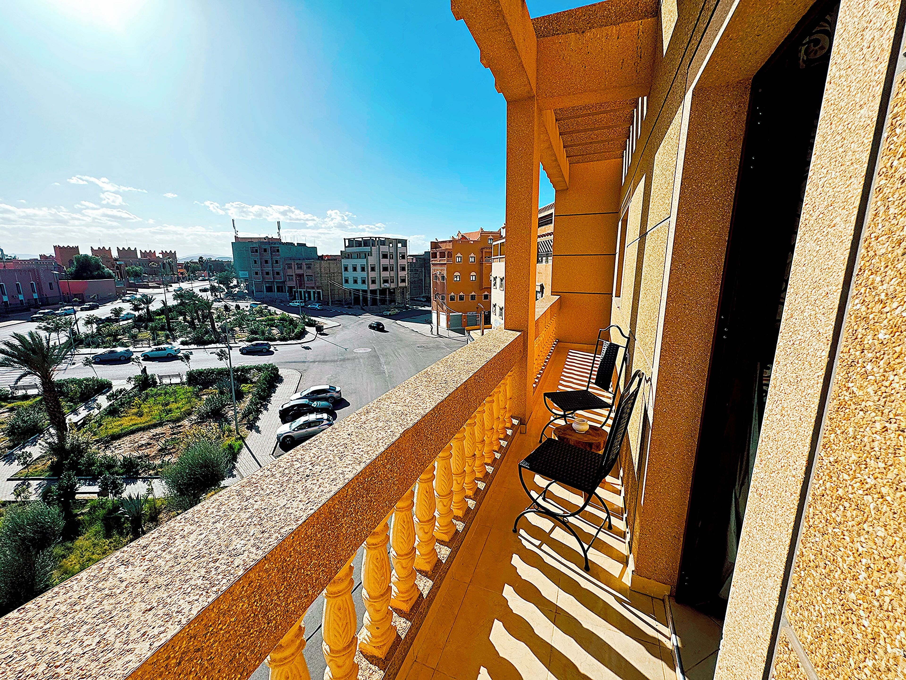 Uma varanda com vista para uma rua da cidade, uma cadeira e uma mesa pequena.