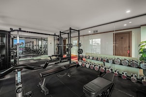 Uma academia com equipamentos de musculação, bancos e halteres.