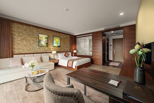 Quarto de hotel com cama, sofá, escrivaninha e um vaso de flores.