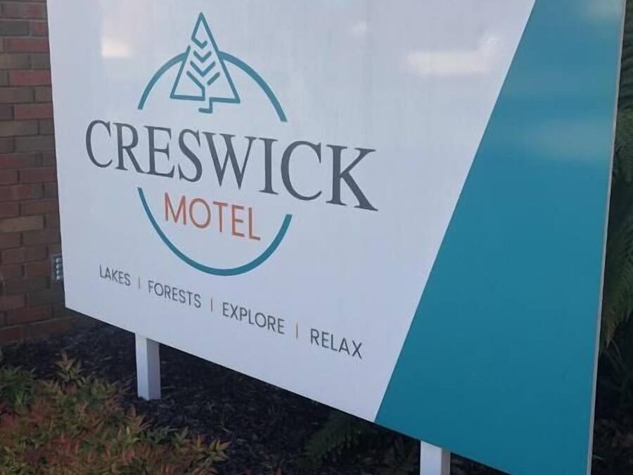 Placa do Creswick Motel, com logotipo e texto indicando sua localização em uma região de lagos e florestas.