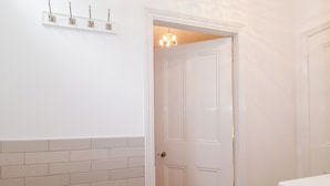 Um corredor com uma porta branca, um interruptor de luz e uma luminária fixada na parede.