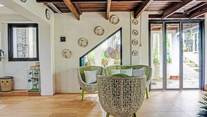 Quarto com cadeiras de vime, aquário de vidro e piso de madeira.