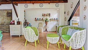 Um quarto aconchegante com cadeiras de vime, uma mesinha e objetos decorativos nas prateleiras.