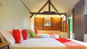Quarto com duas camas, vigas de madeira, um quadro e vista para o verde lá fora.