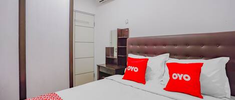 Quarto de hotel com cama, guarda-roupa, mesa de cabeceira e ar condicionado fixado na parede.