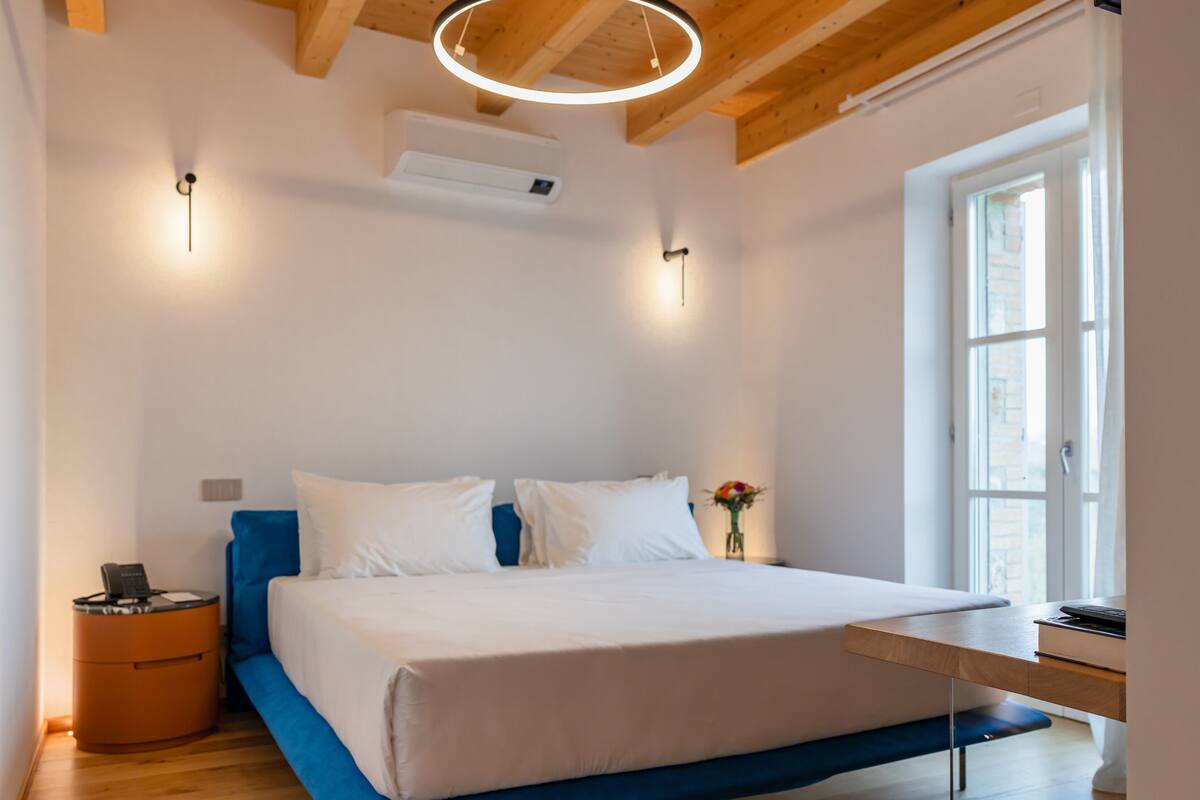 Um quarto com uma cama, mesa de cabeceira e janela.