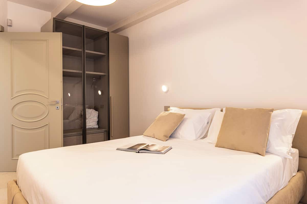 Quarto com cama, guarda-roupa e mesa de cabeceira.