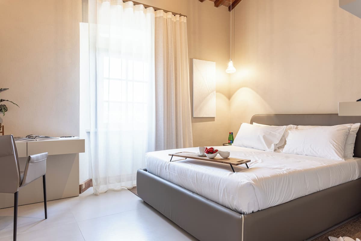 Quarto moderno com cama, mesa de cabeceira e escrivaninha com cadeira.