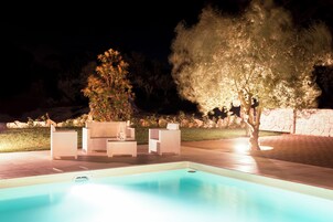 Piscina com espreguiçadeiras e uma árvore.