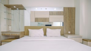 Quarto moderno com uma cama grande, cabeceira de madeira, mesas de cabeceira e um guarda-roupa embutido com portas de vidro.