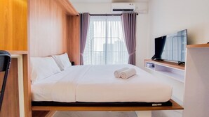 Quarto de hotel com cama, televisão em uma estante e aparelho de ar condicionado.