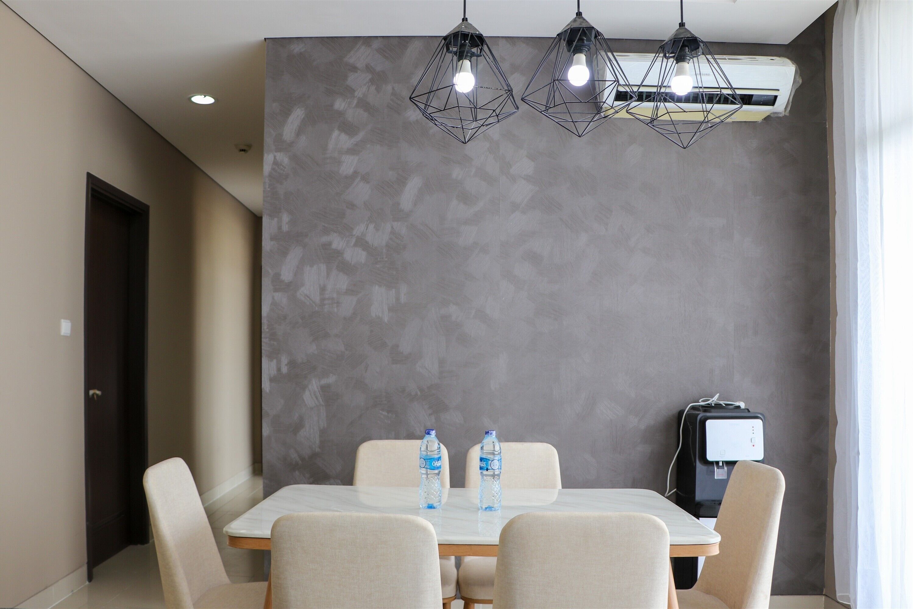 Uma área de jantar moderna com uma mesa, cadeiras e luminárias pendentes.