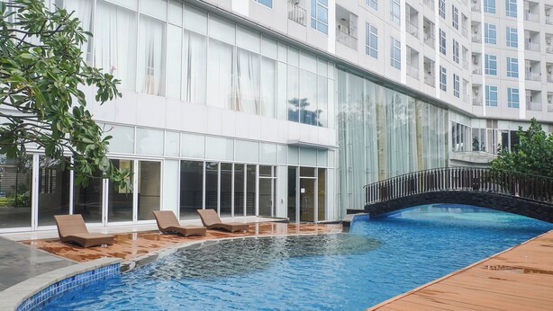 Um hotel moderno com piscina, espreguiçadeiras e uma ponte de pedra.