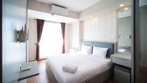 Quarto de hotel moderno com uma cama grande, mesa de cabeceira, espelho e ar condicionado instalado.