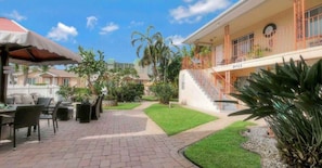 Pátio de hotel com área de estar externa, escadaria e um edifício com a inscrição "OFFICE".