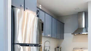 Cozinha moderna com eletrodomésticos de aço inoxidável, armários cinzas e piso ladrilhado.