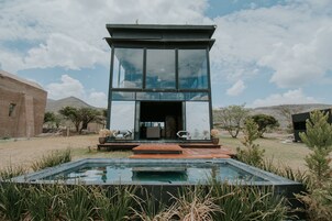 Uma casa moderna com fachada de vidro, piscina e área de varanda.