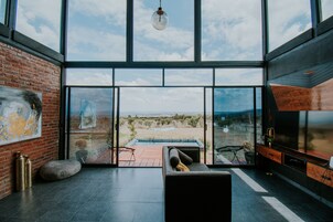 Interior moderno com grandes janelas, parede de tijolos e vista para paisagem desértica.