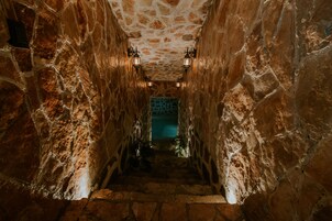 Uma escadaria de pedra com teto trabalhado e arandelas na parede.