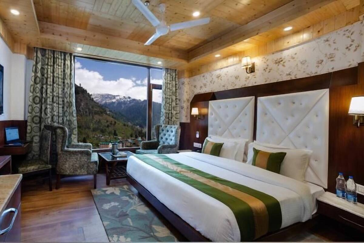 Quarto de hotel com uma cama grande, uma escrivaninha, uma cadeira e uma televisão.