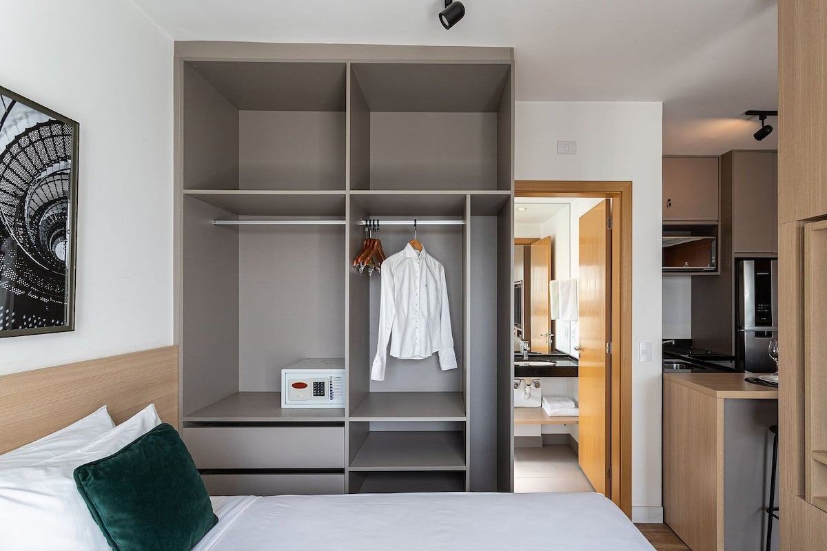 Quarto com cama, mesa de cabeceira, guarda-roupa com espaço para pendurar e vista para o banheiro.