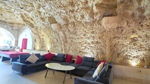 Ampla sala de estar com um sofá seccional grande, uma mesa de centro e uma parede de pedra.
