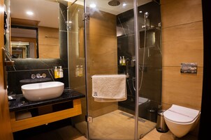 Uma casa de banho moderna com chuveiro de vidro, lavatório branco e sanita.