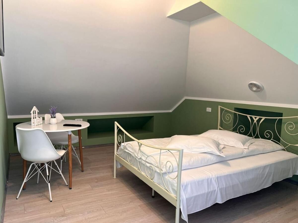 Um quarto pequeno e bem iluminado, com uma cama, uma escrivaninha e uma cadeira.