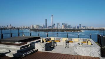 Terraço no telhado com assentos e vista para o horizonte urbano sobre a água.