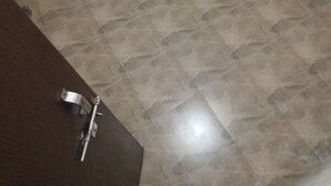 Casa de banho com sanita, chuveiro e parede revestida a azulejos com um desenho de árvore.