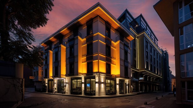 Um hotel moderno com entrada em esquina, janelas amplas e fachada bem iluminada.