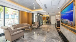 Um lobby moderno com um sofá grande, uma mesa de centro e um aquário.