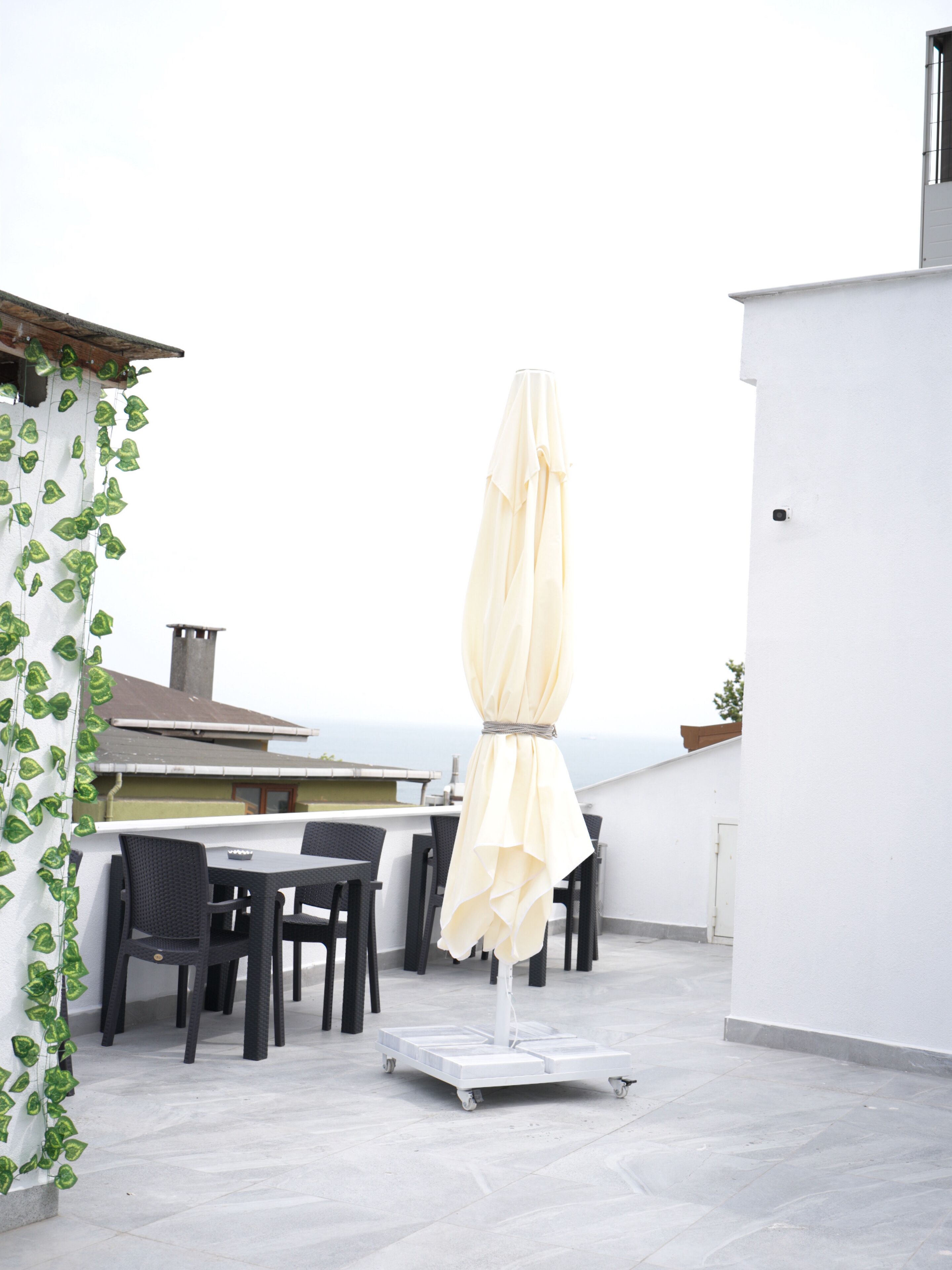Terraço no telhado com mesa, cadeiras, guarda-sol e vista para o mar.